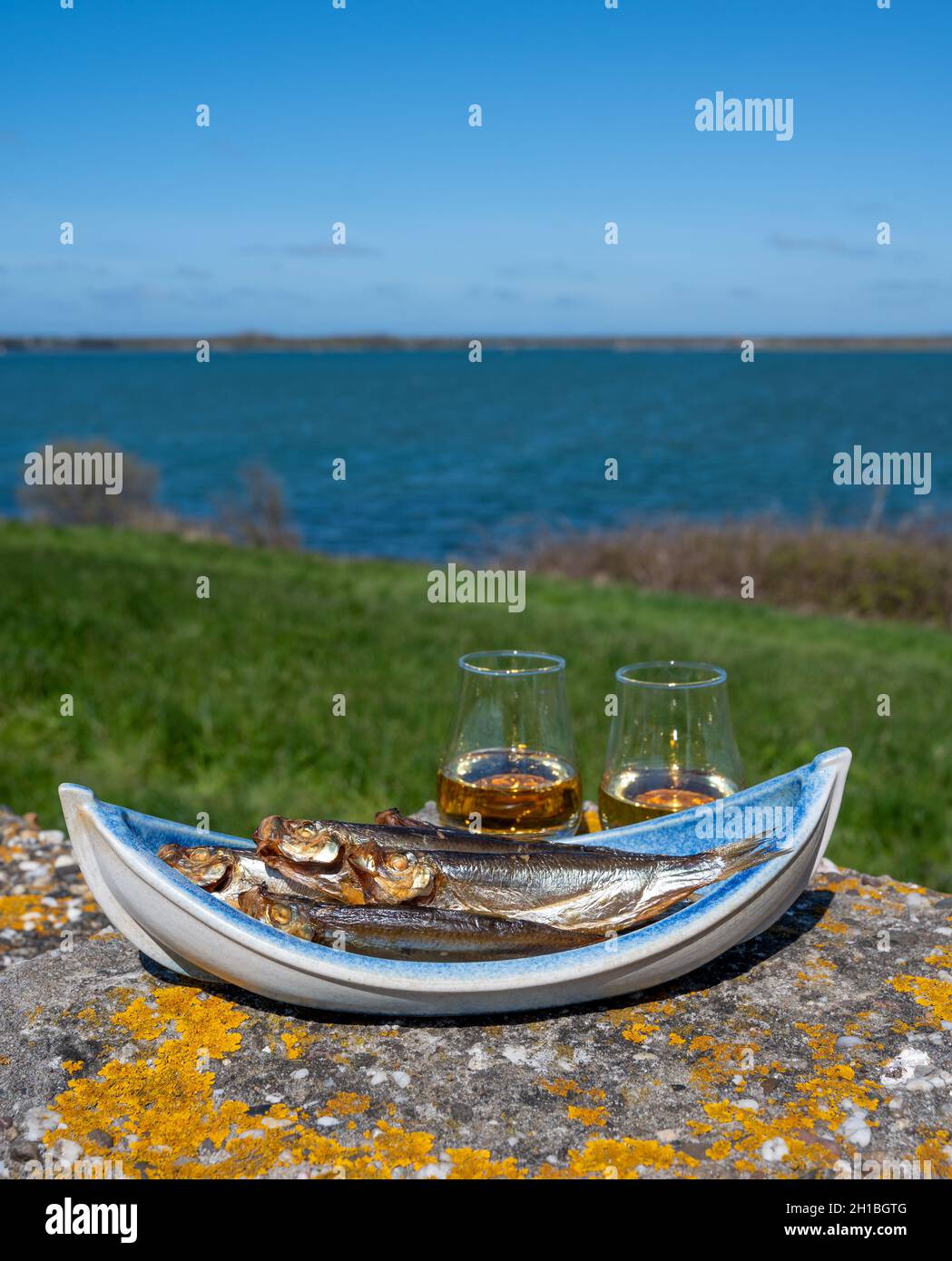 Smoked sprattus or sprats sea fish served outdoor with view on blue sea ...