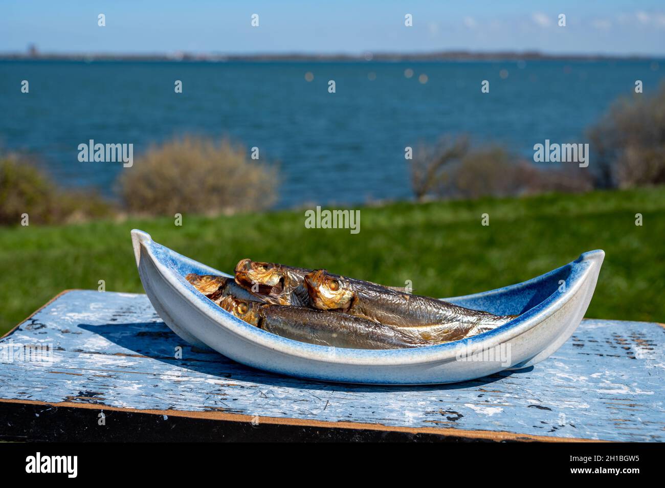 Smoked sprattus or sprats sea fish served outdoor with view on blue sea ...
