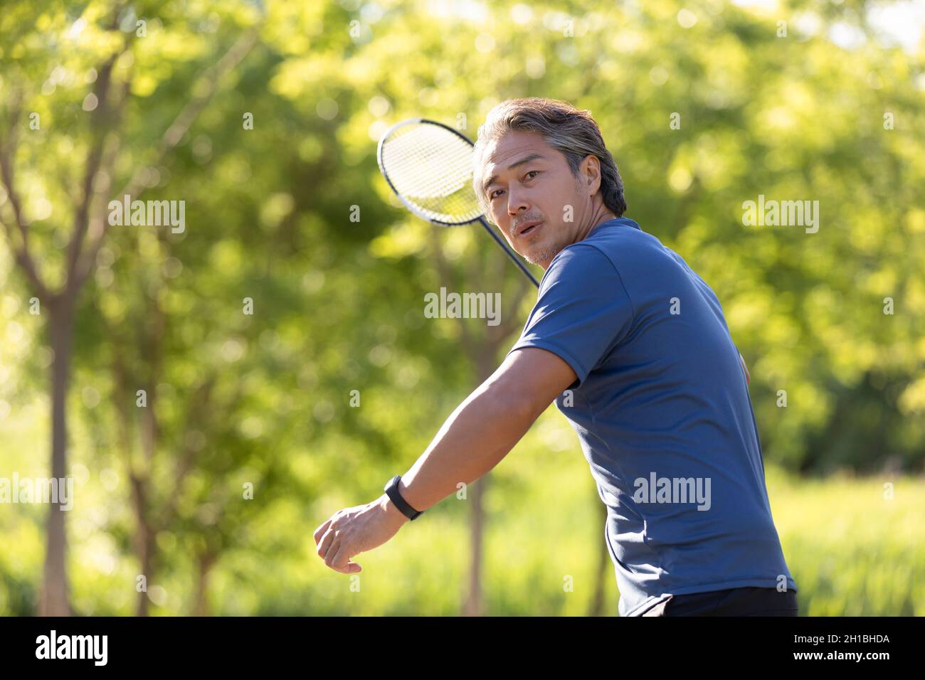 Mature man playing badminton outdoors Stock Photo - Alamy