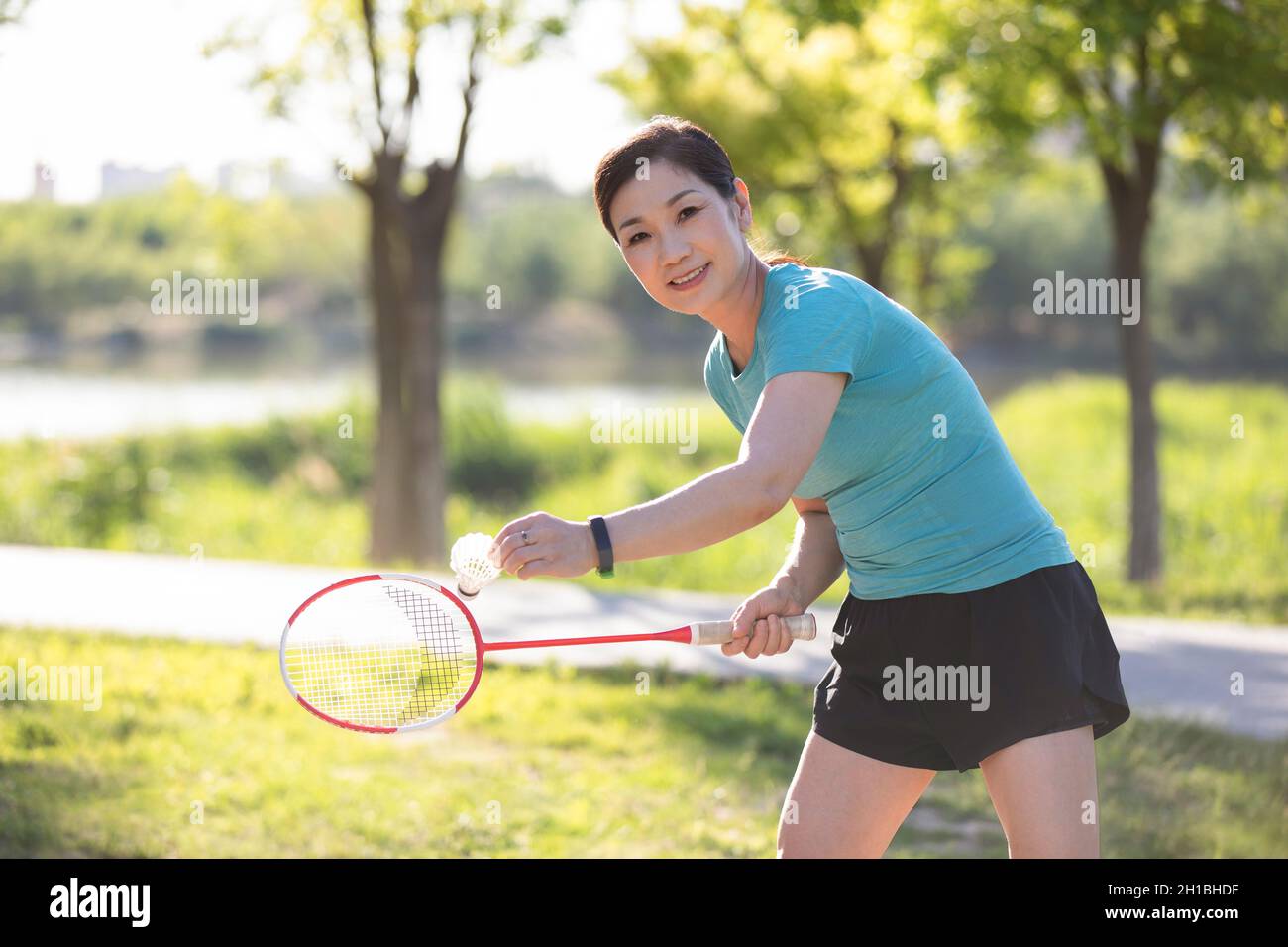 Happy mature woman playing badminton outdoors Stock Photo - Alamy