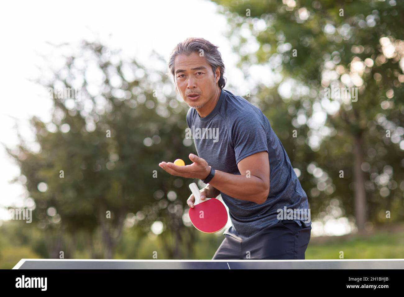 Happy mature man playing table tennis outdoors Stock Photo - Alamy