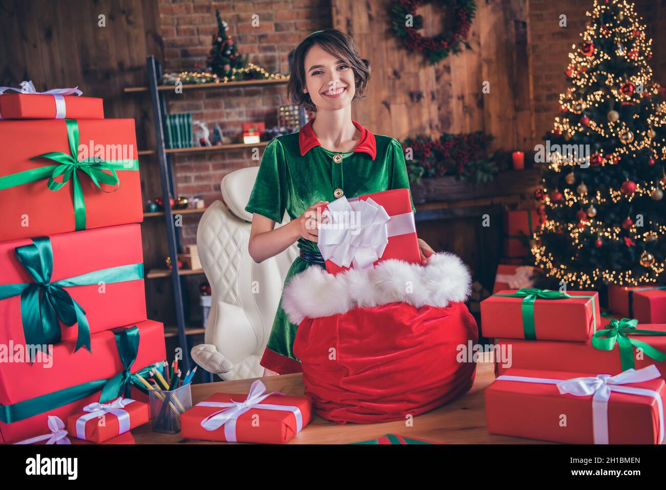 Portrait of attractive cheerful girl elf packing order giftbox service ...