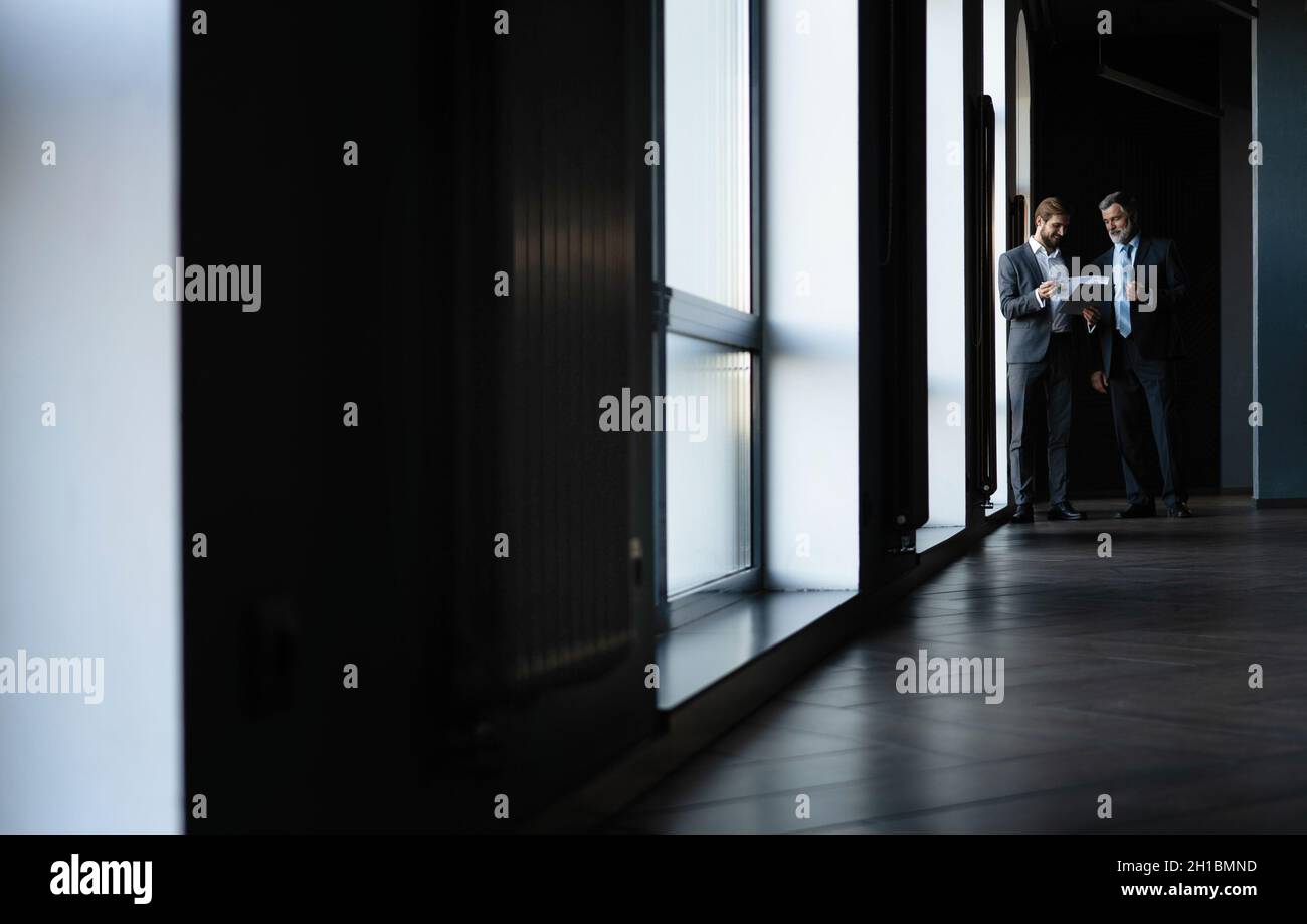 Two colleagues communicating in corridor, partners walking in the ...
