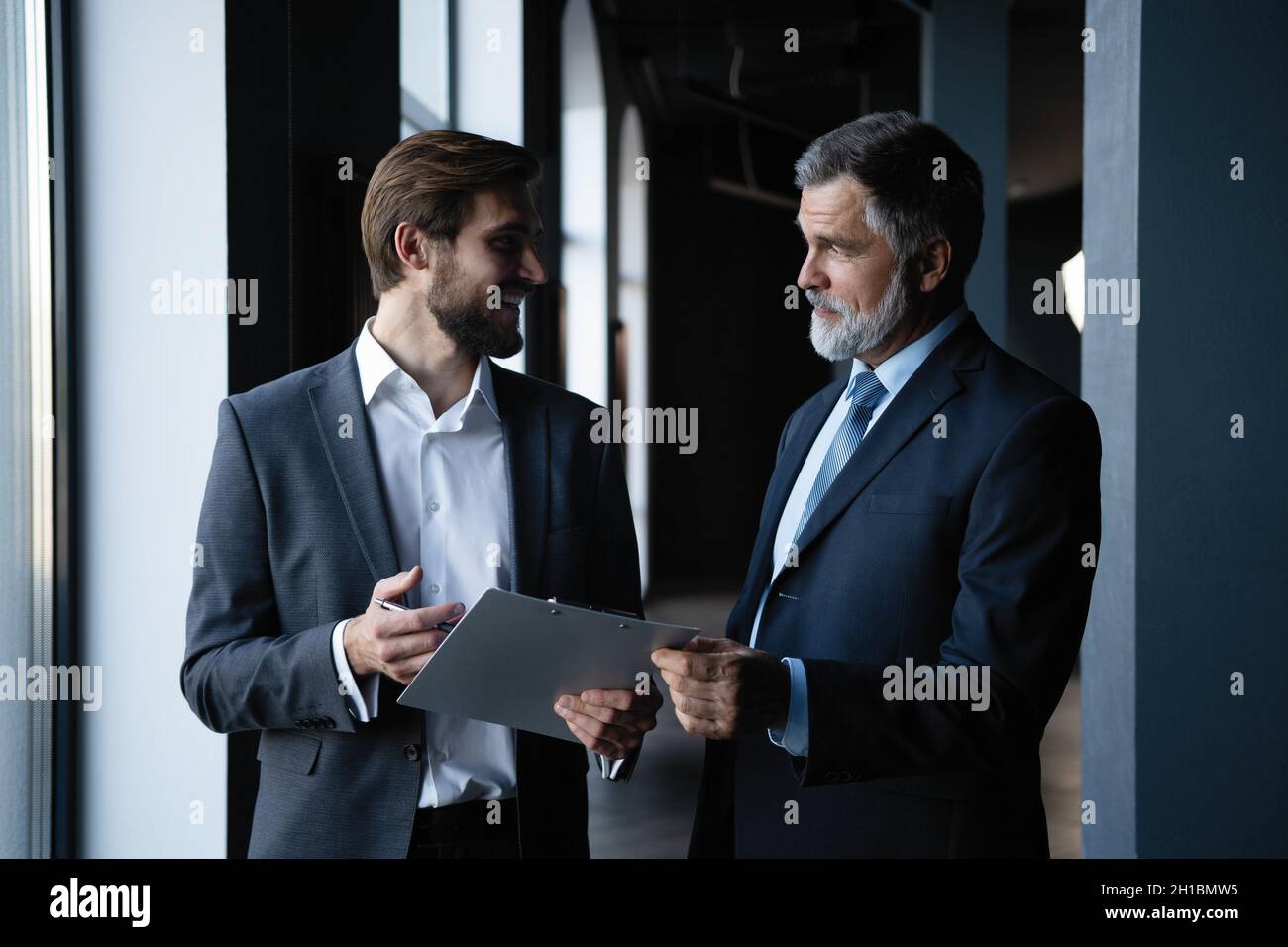 Two colleagues communicating in corridor, partners walking in the ...