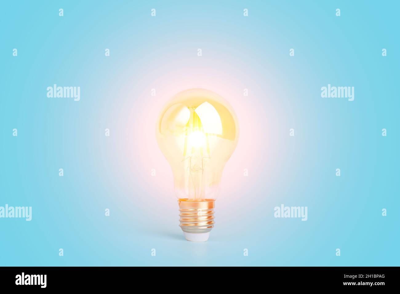 Knowledge and idea concept. Light bulb with light on a blank blue ...
