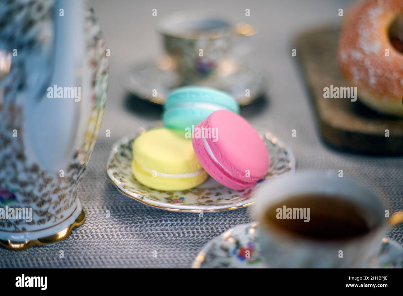 Traditional table with cup of tea and tea pot and colorful macaron ...