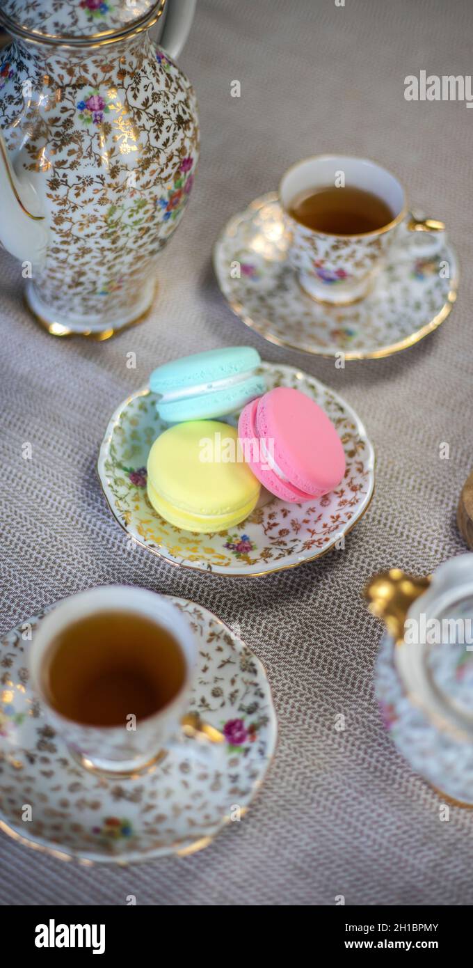 Traditional table with cup of tea and tea pot and colorful macaron ...