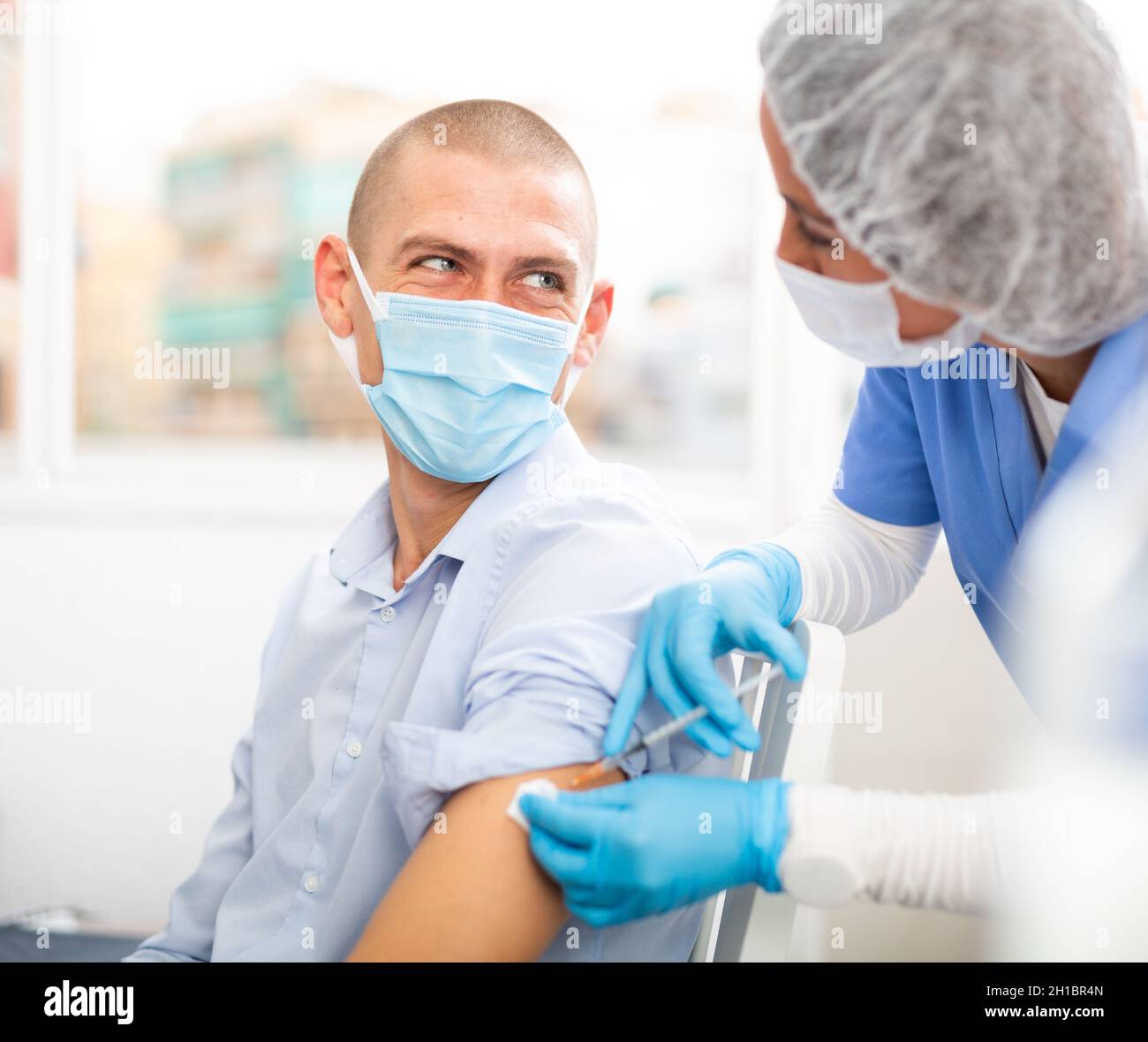 Professional nurse giving vaccine injection to man Stock Photo - Alamy