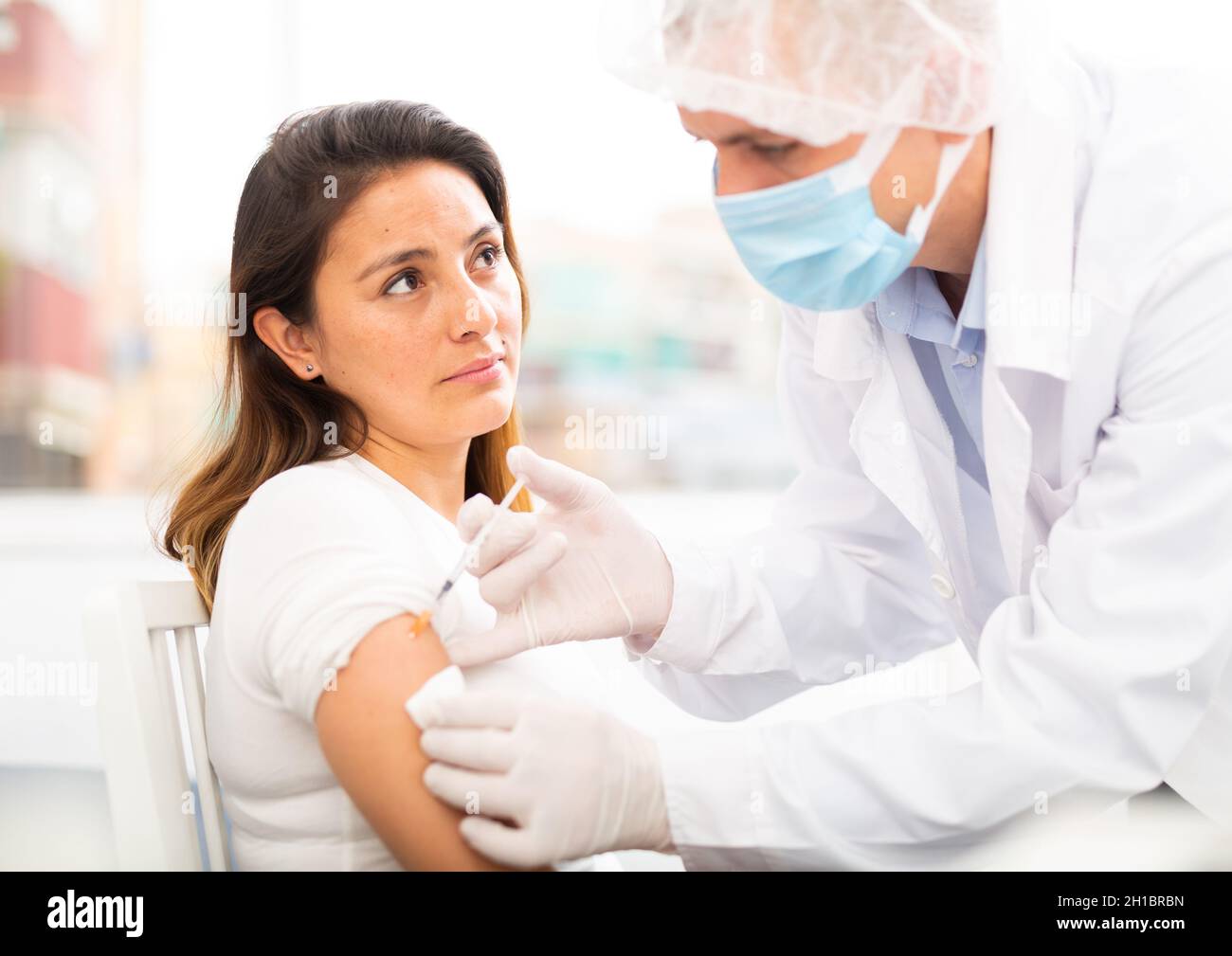 Man doctor making injection to woman patient Stock Photo - Alamy