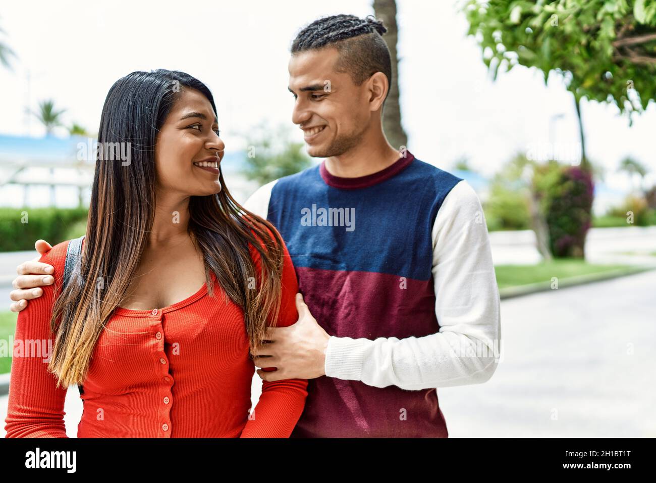 Young latin couple smiling happy and hugging walking at the street of ...