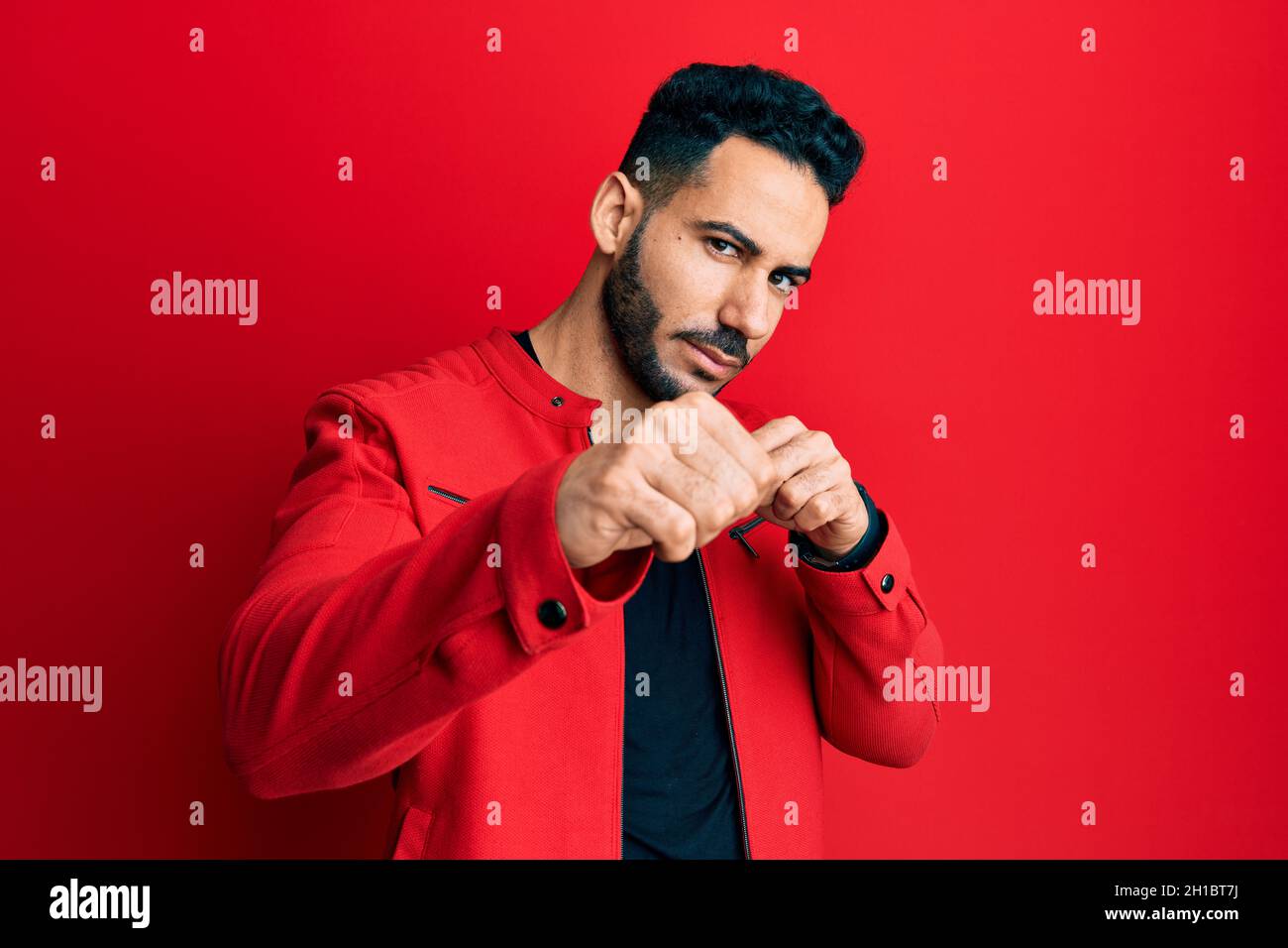 Young hispanic man wearing red leather jacket punching fist to fight ...