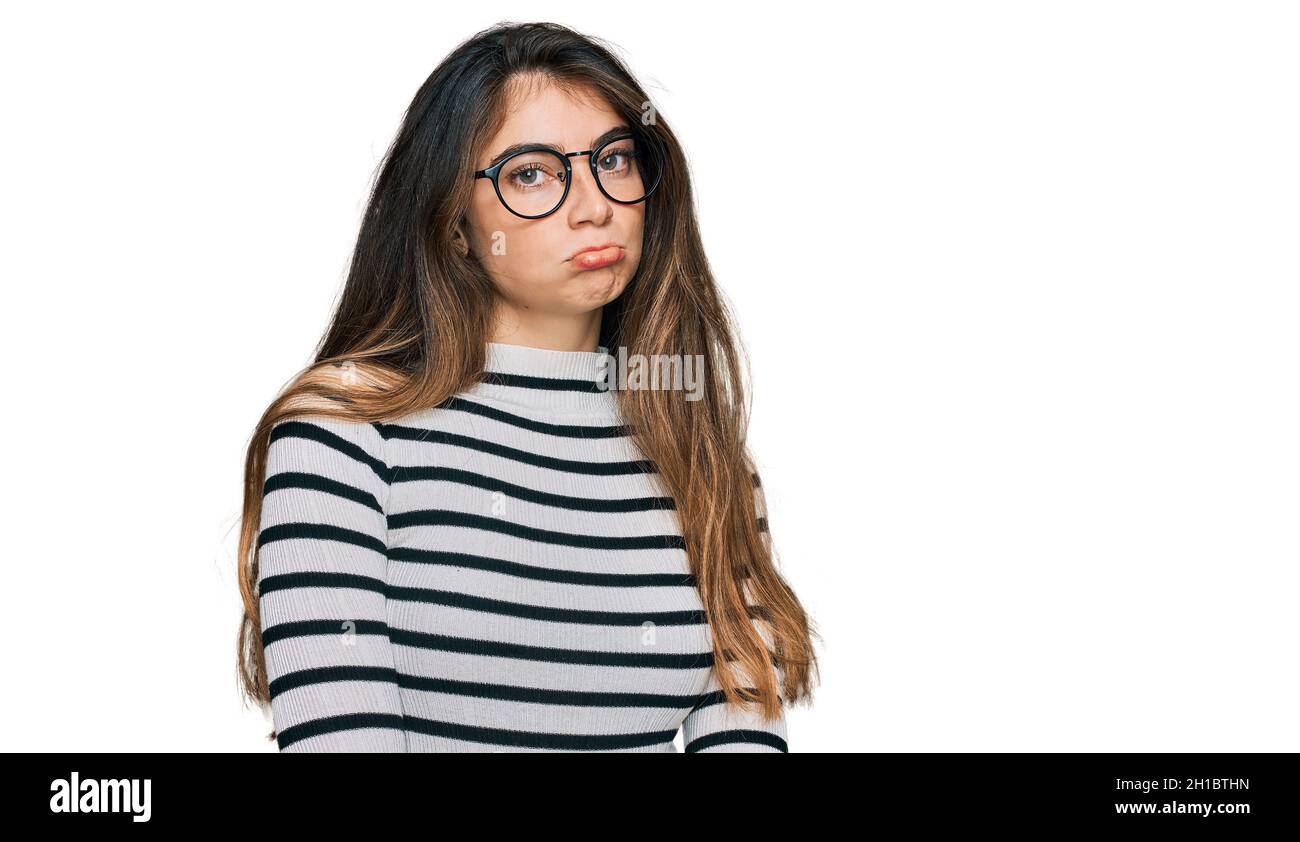 Young beautiful teen girl wearing casual clothes and glasses depressed ...