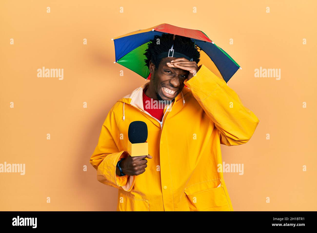 Young african american journalist man wearing yellow raincoat and ...