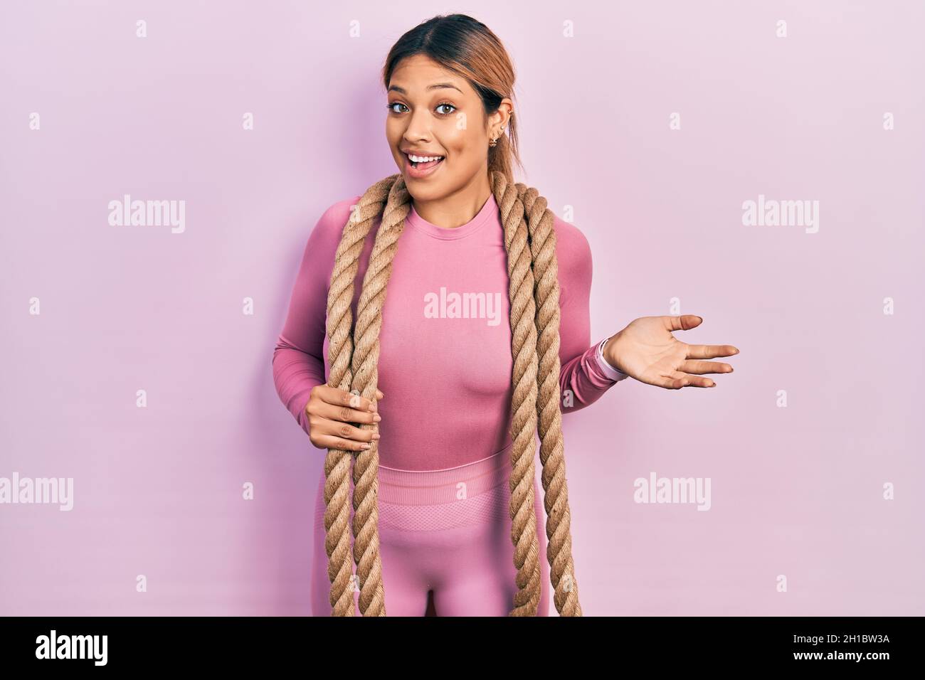 Beautiful hispanic woman training with battle rope celebrating ...