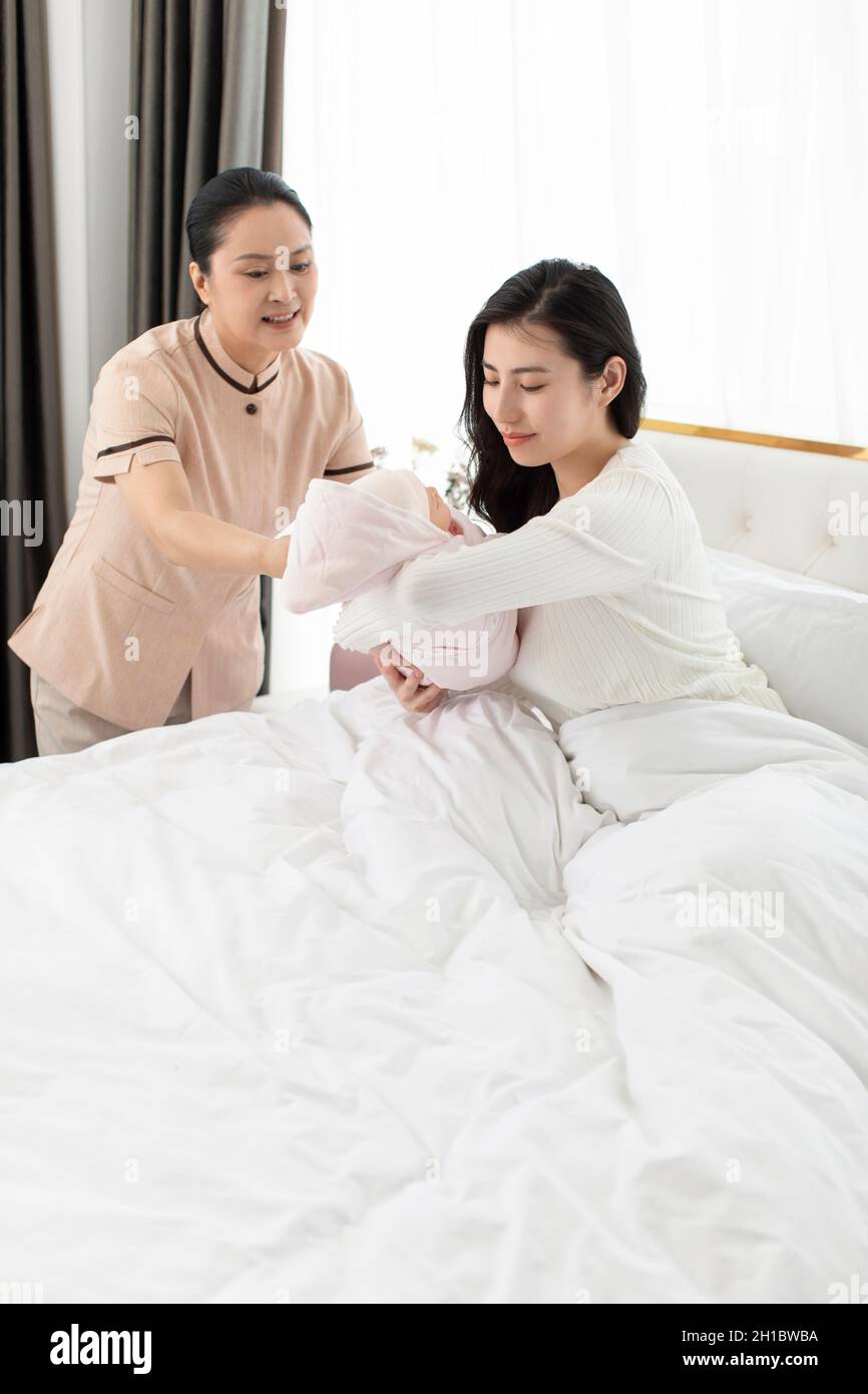 Confinement nurse taking care of young mother and baby Stock Photo - Alamy