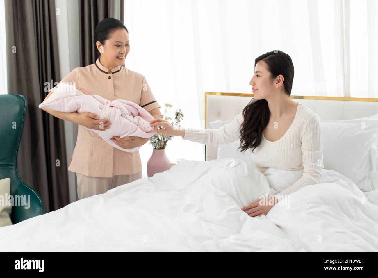 Confinement nurse taking care of young mother and baby Stock Photo - Alamy
