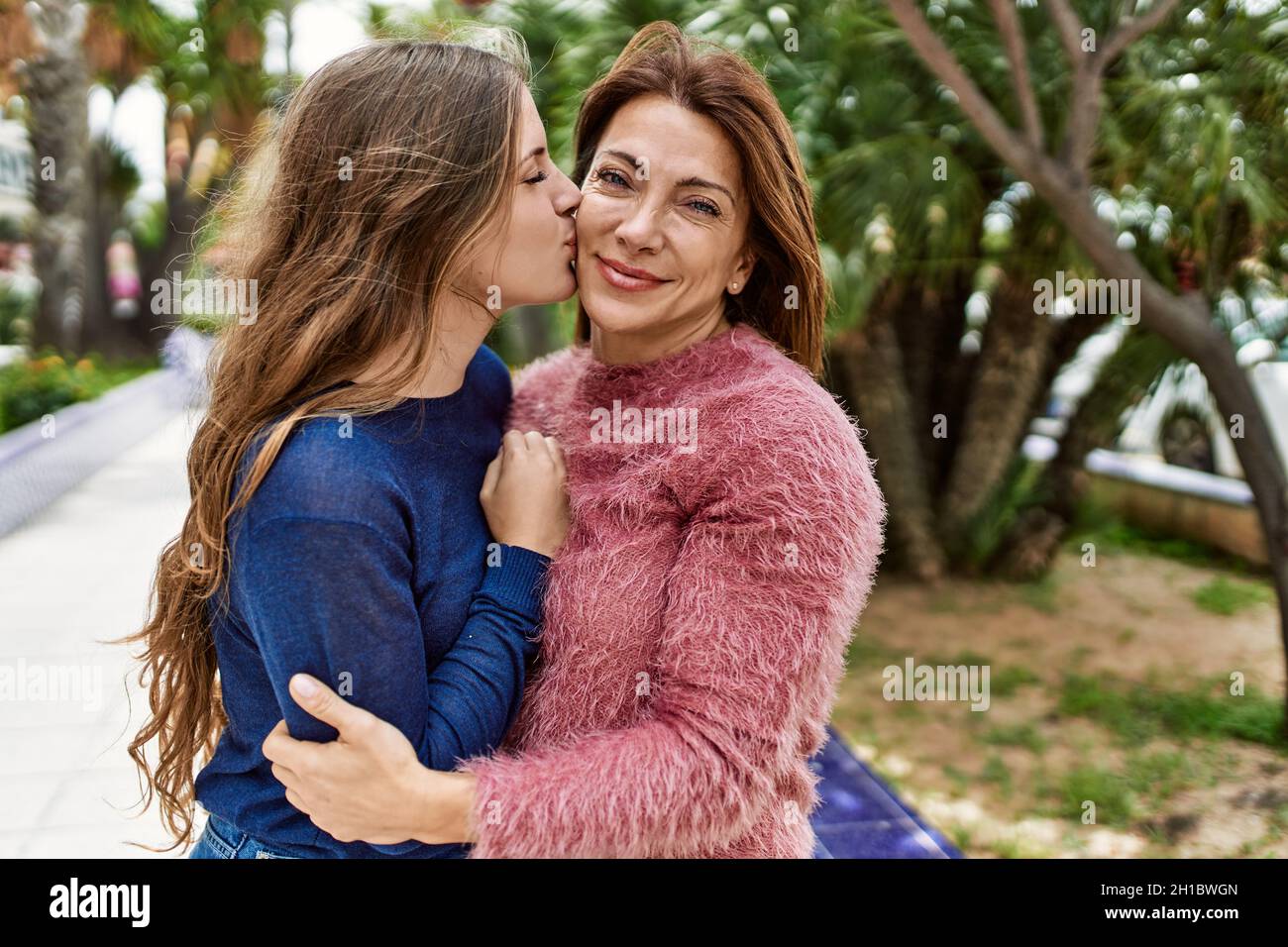 Mother and daughter hugging each other and kissing at park Stock Photo - Alamy