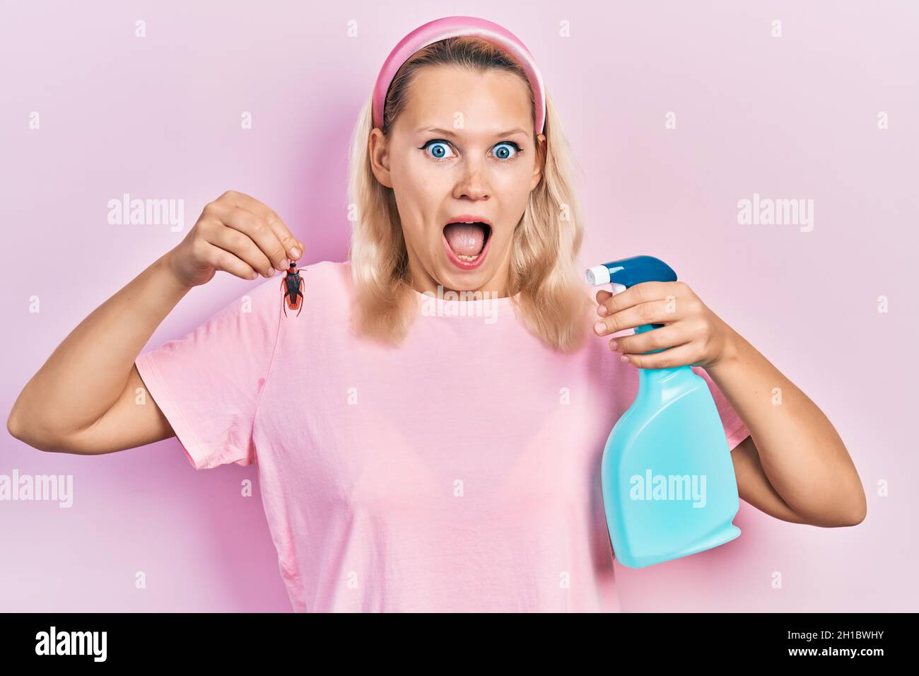 Beautiful caucasian blonde woman holding cockroach and pesticide ...
