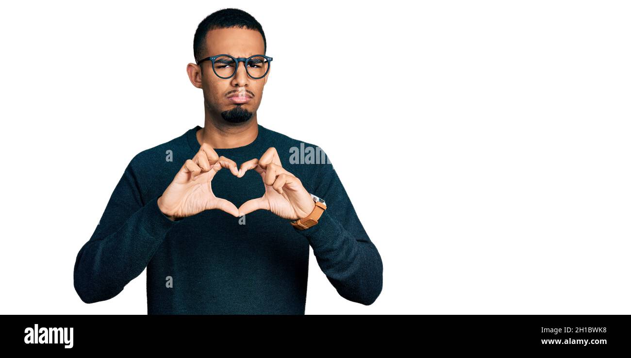 Young african american man doing heart symbol with hands skeptic and ...