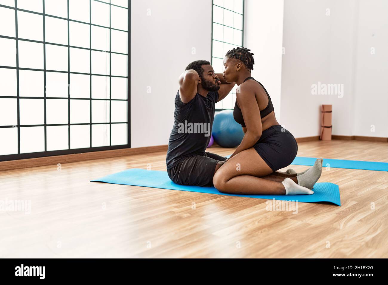 Young african american sporty couple kissing and doing abs exercise at ...