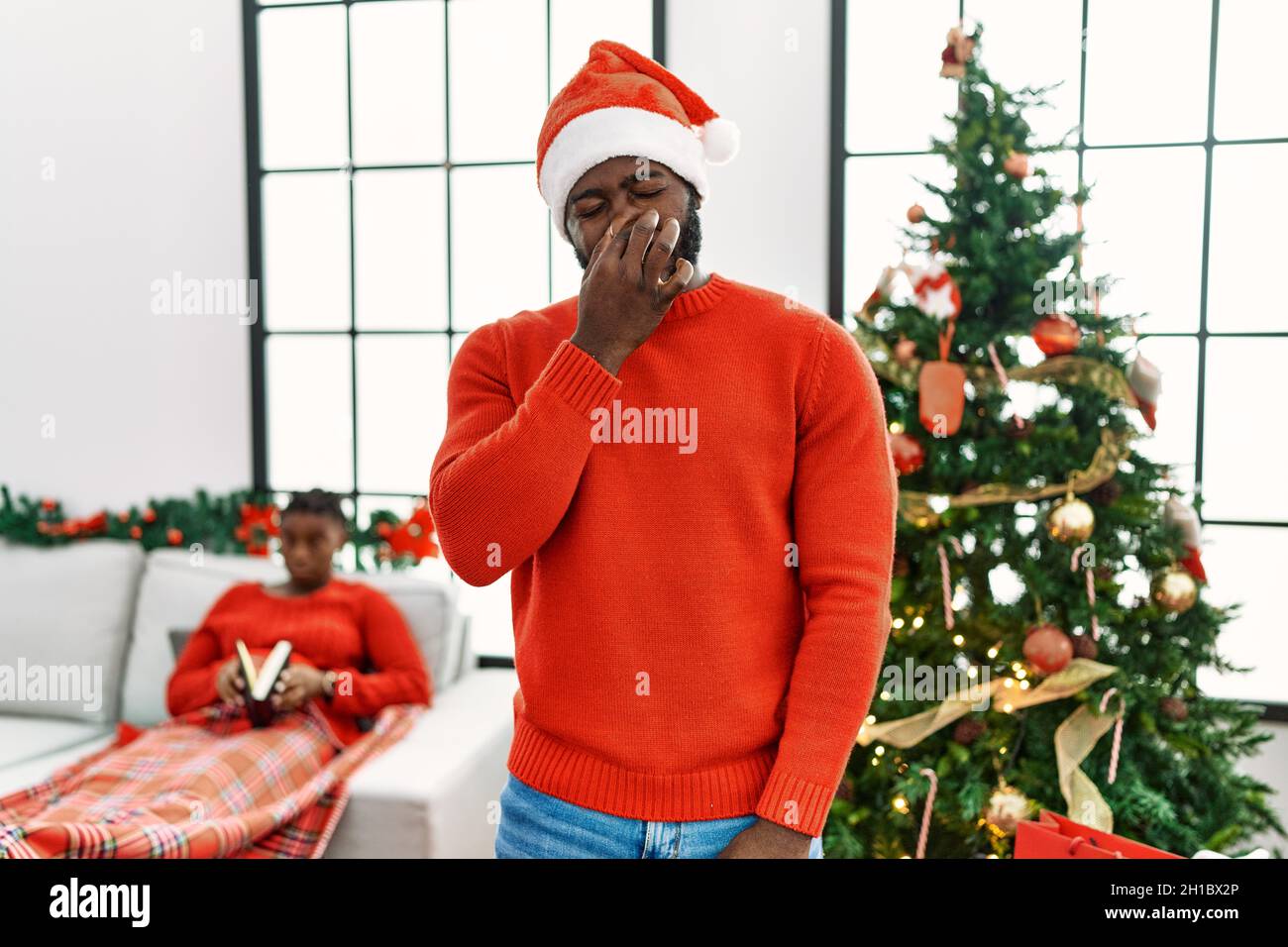 Young african american man standing by christmas tree smelling ...