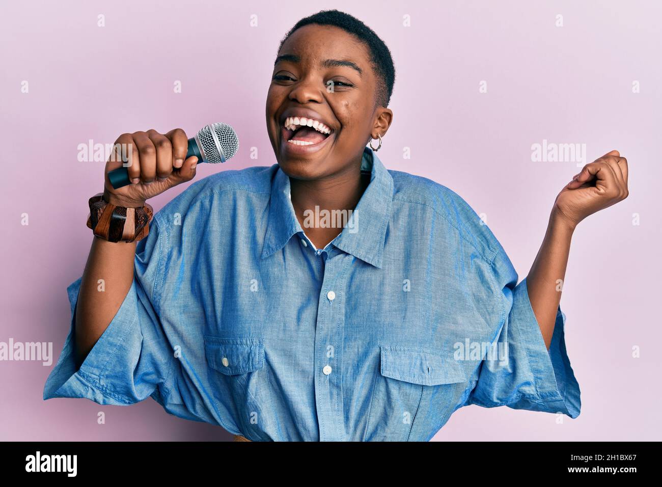 Young african american woman singing song using microphone screaming ...