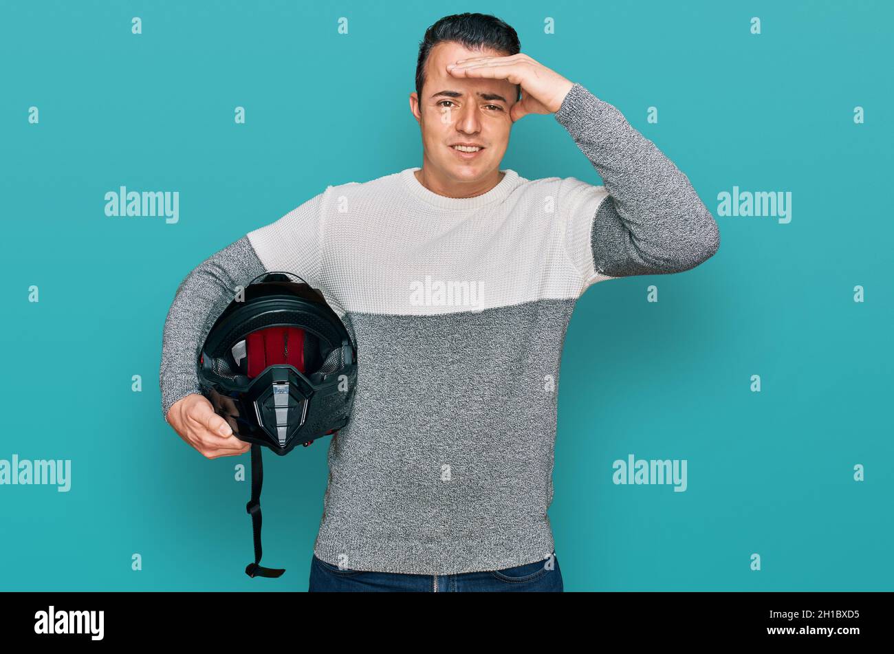 Handsome young man holding motorcycle helmet stressed and frustrated ...