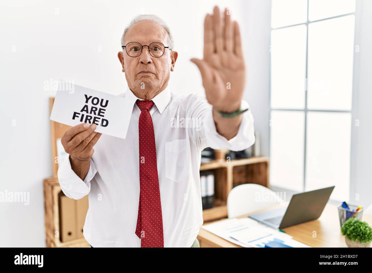 Senior business man holding you are fired banner at the office with ...
