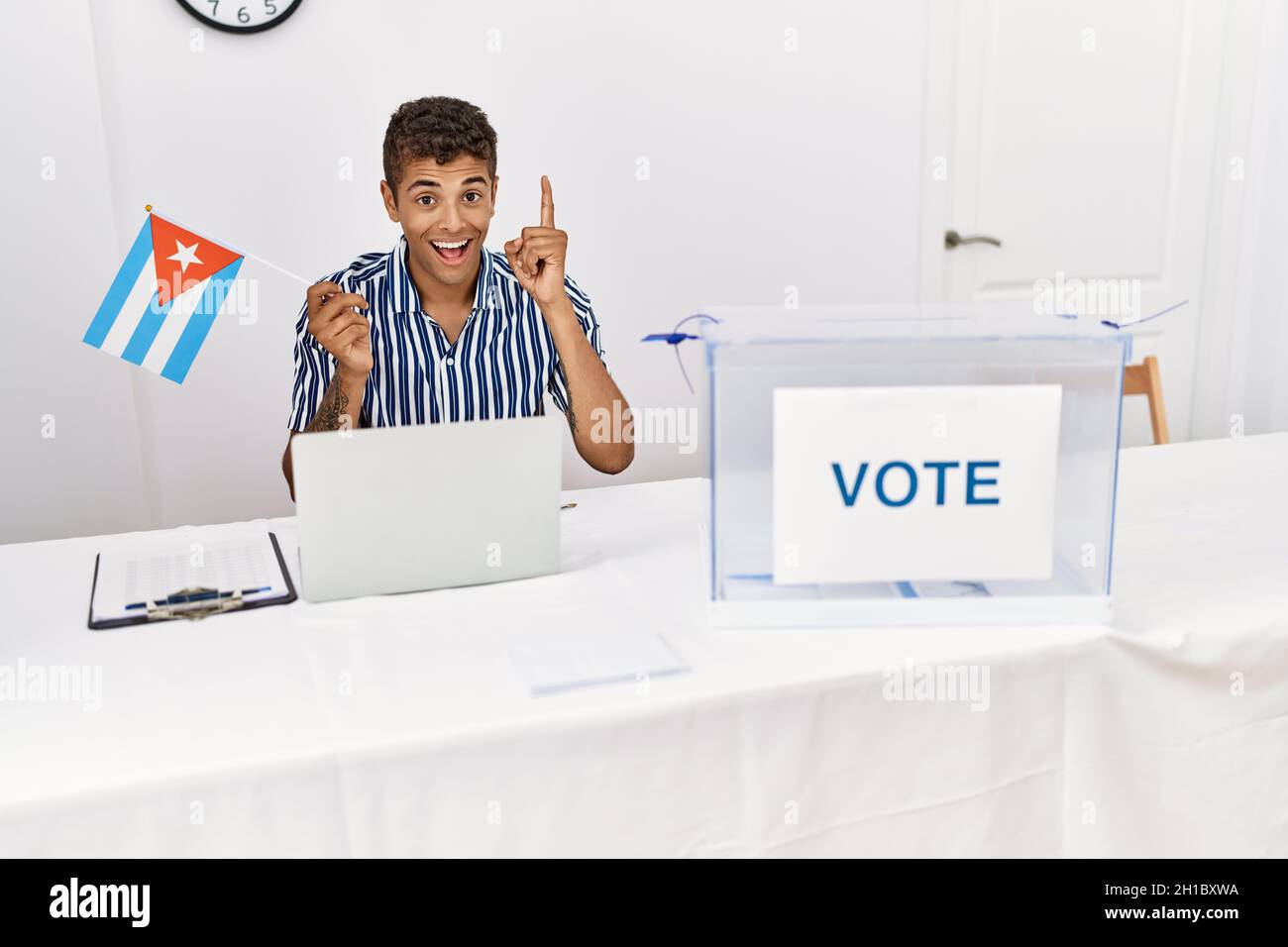 Young handsome hispanic man at political campaign election holding cuba ...