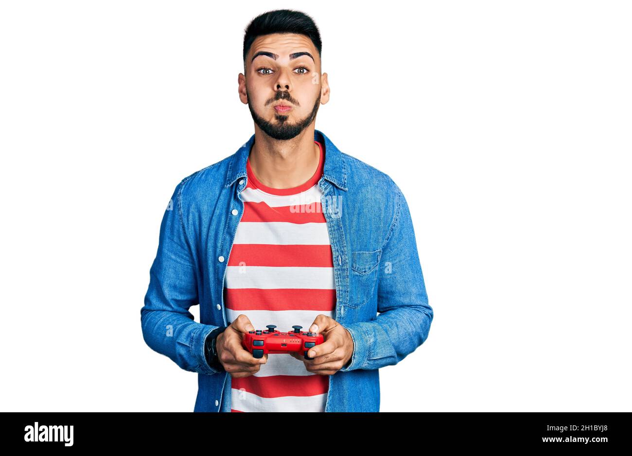 Young hispanic man with beard playing video game holding controller ...