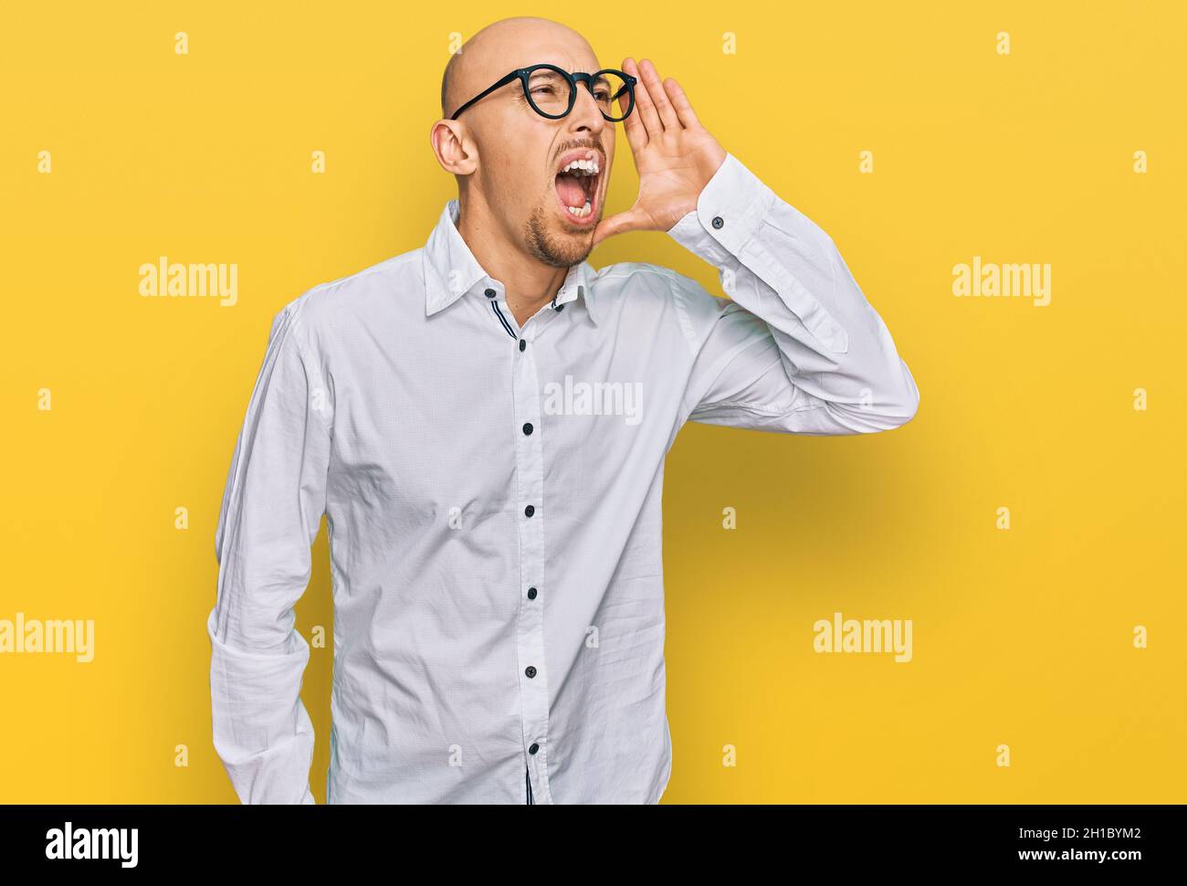 Bald man with beard wearing business shirt and glasses shouting and ...