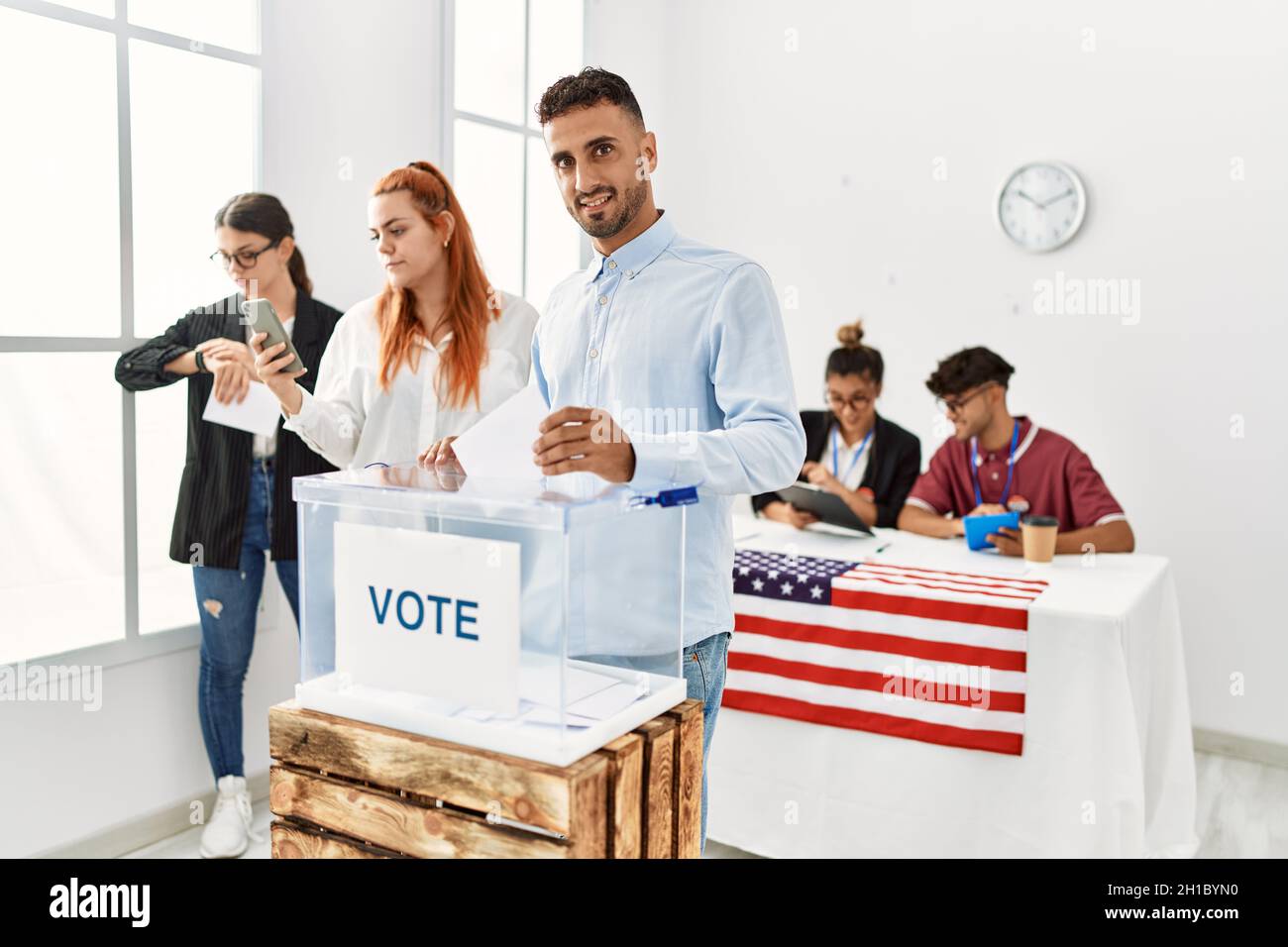 Young american voter man smiling happy putting ballot in voting box at ...
