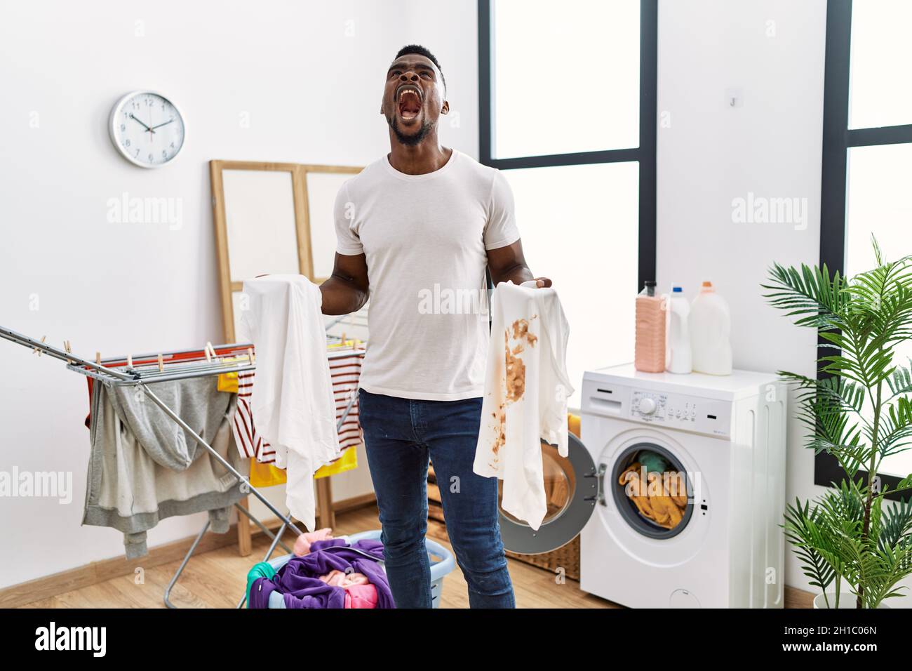 Young african man holding clean white t shirt and t shirt with dirty ...