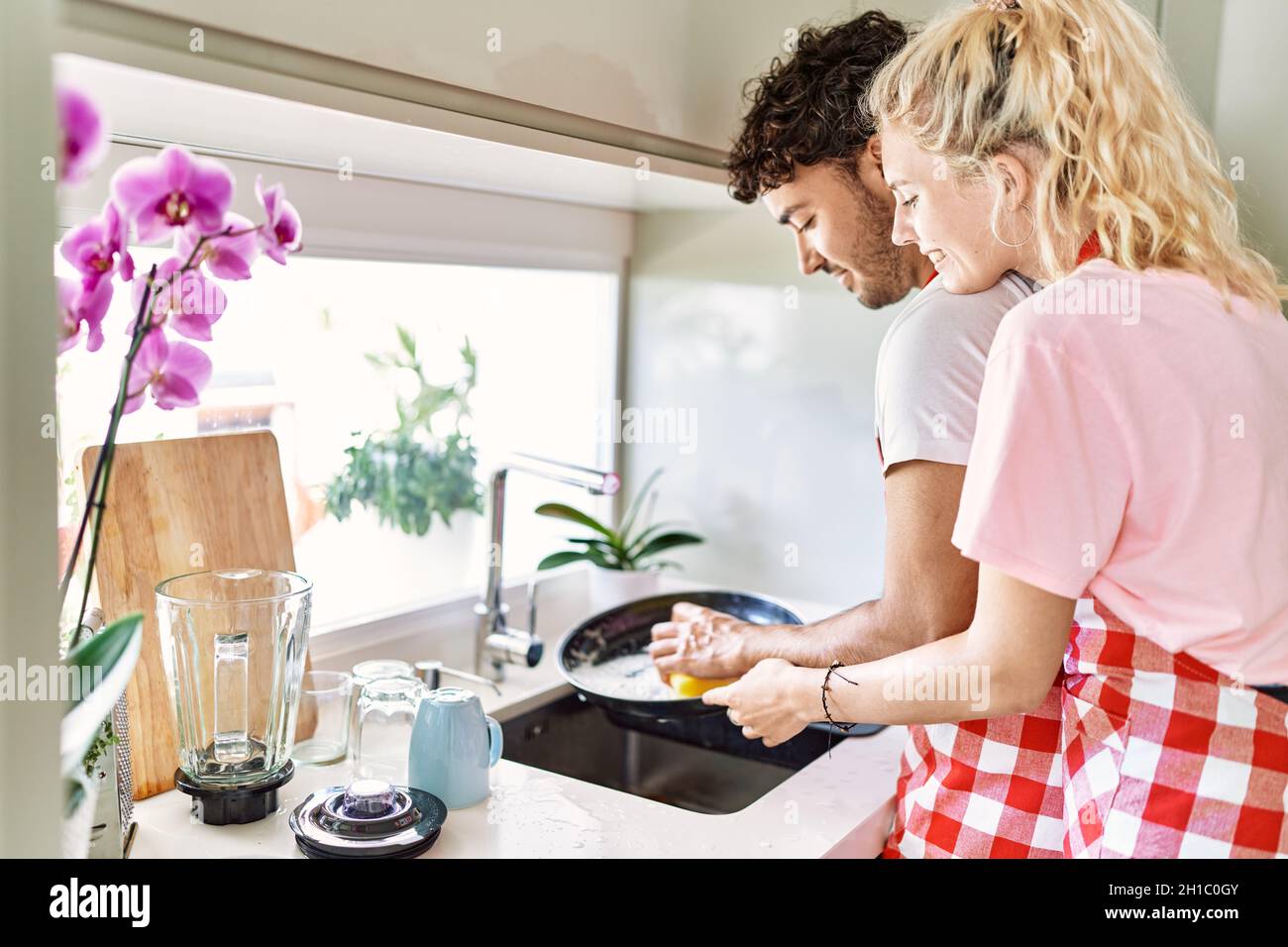 Young couple smiling happy and hugging washing dishes at kitchen Stock ...