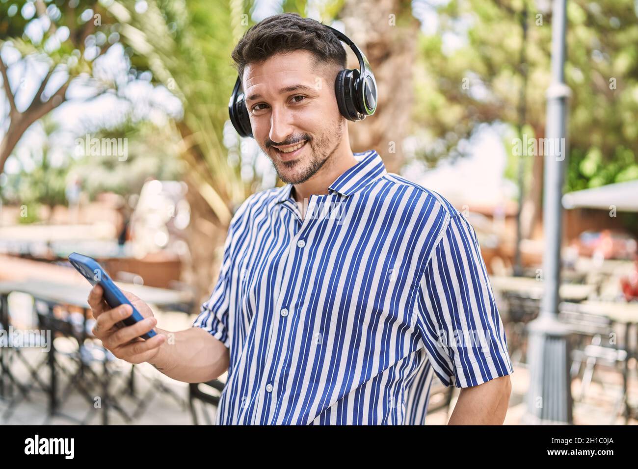 Young handsome man wearing headhphones using smartphone at park Stock ...