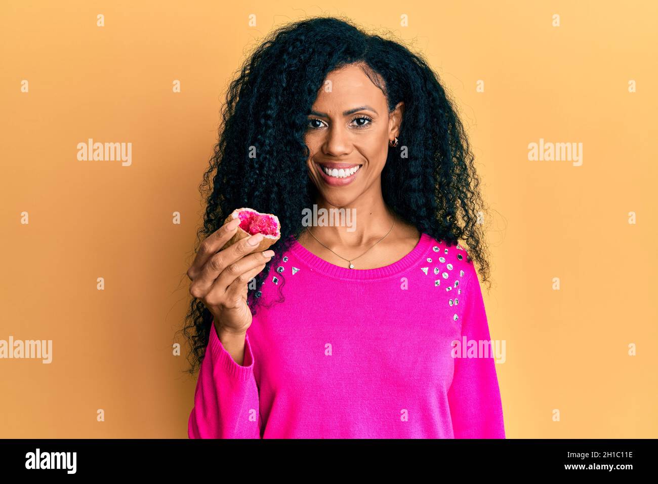 Middle age african american woman holding geode looking positive and ...