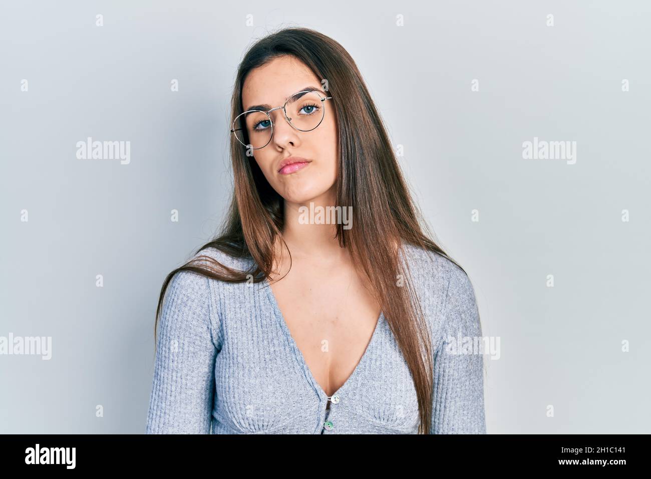 Young brunette teenager wearing casual sweater and glasses relaxed with ...