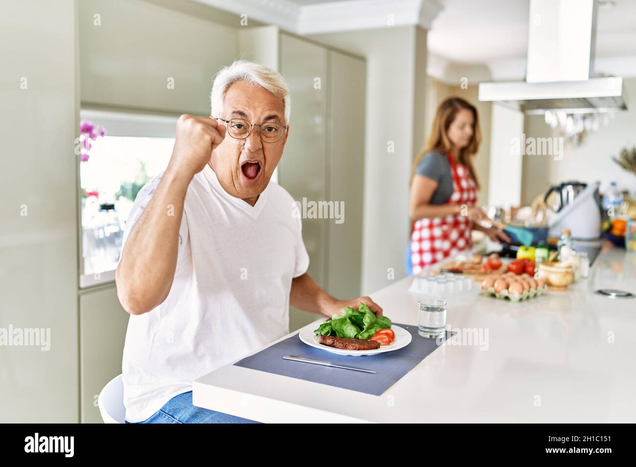 Middle age hispanic couple eating healthy meal at home annoyed and ...