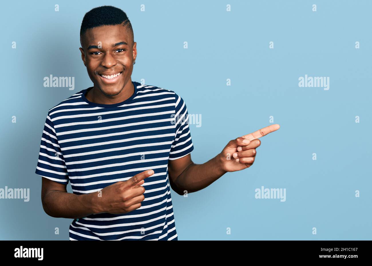 Young african american man pointing with fingers to the side smiling ...