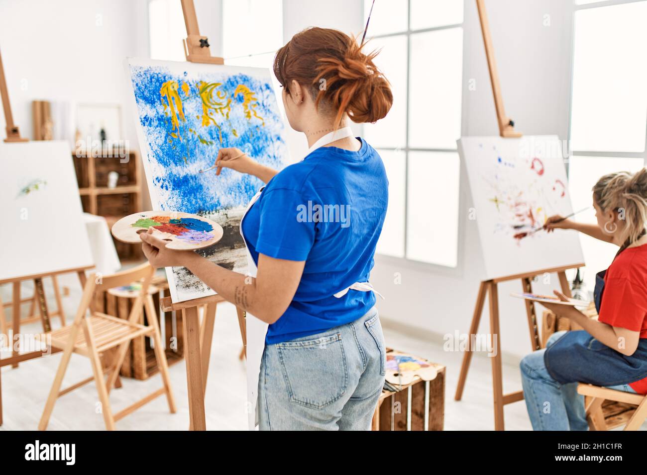 Two artist student women on back view painting at art school Stock ...
