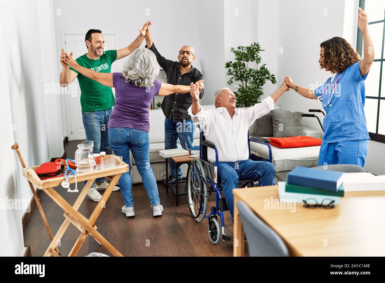 Group of retired people having party dancing with doctor and volunteer ...