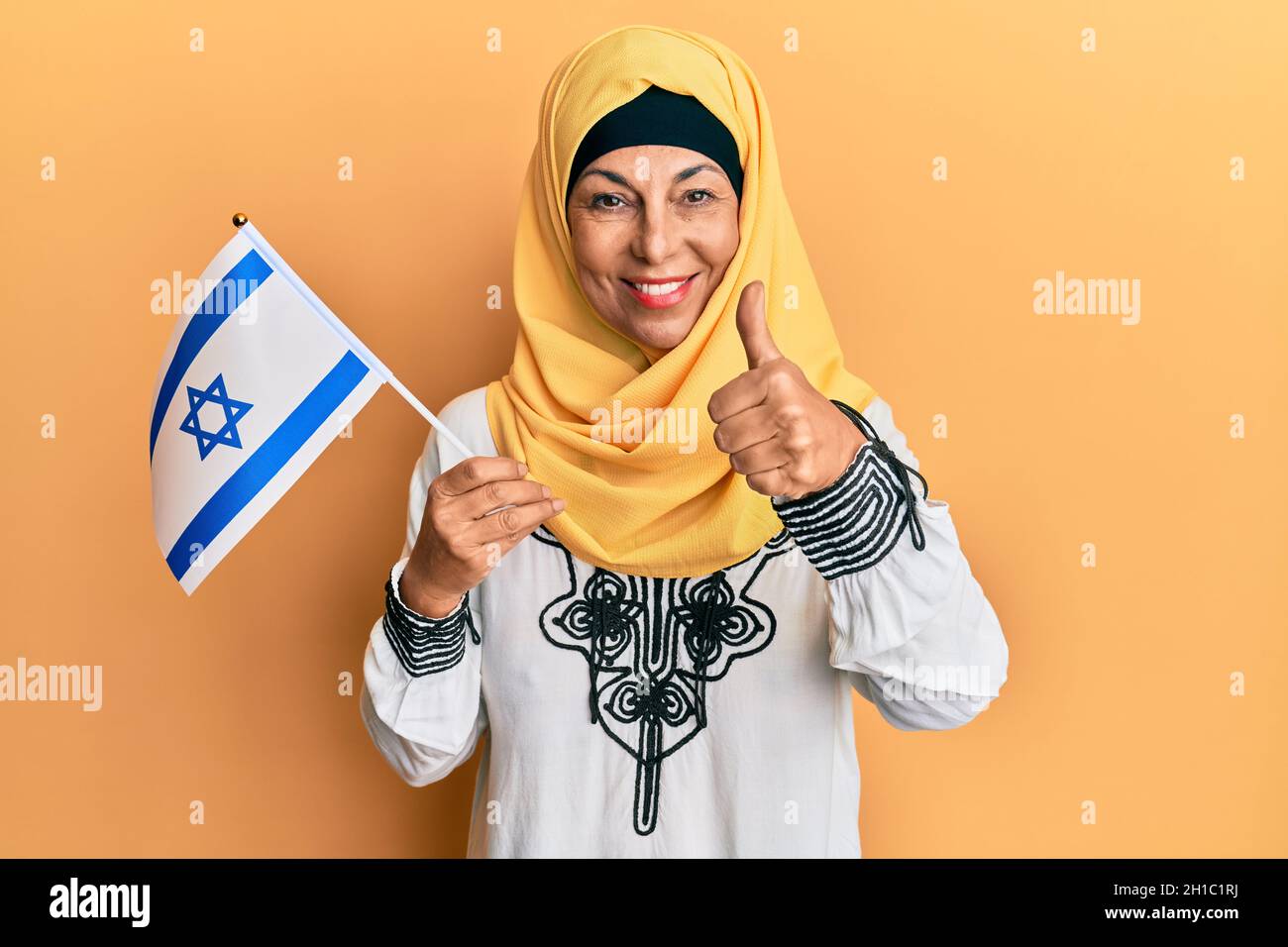 Middle age hispanic woman wearing hijab holding israel flag smiling ...