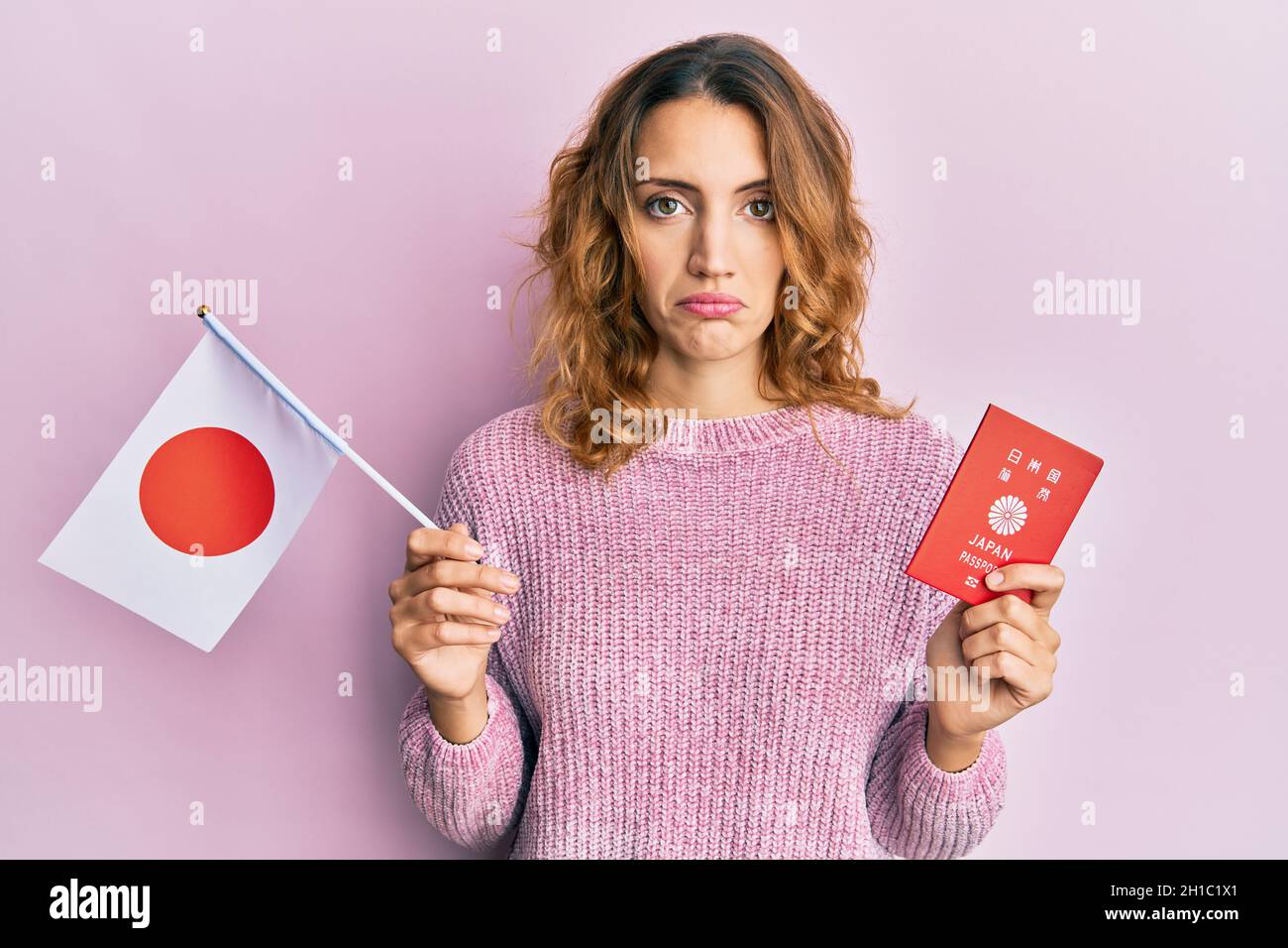 Young caucasian woman holding japan flag and passport depressed and ...