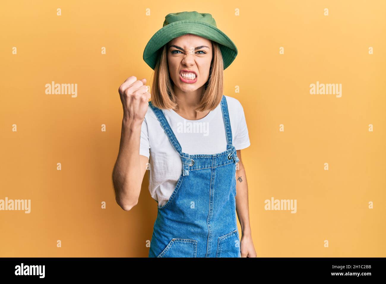 Young caucasian blonde woman wearing denim jumpsuit and hat with 90s ...