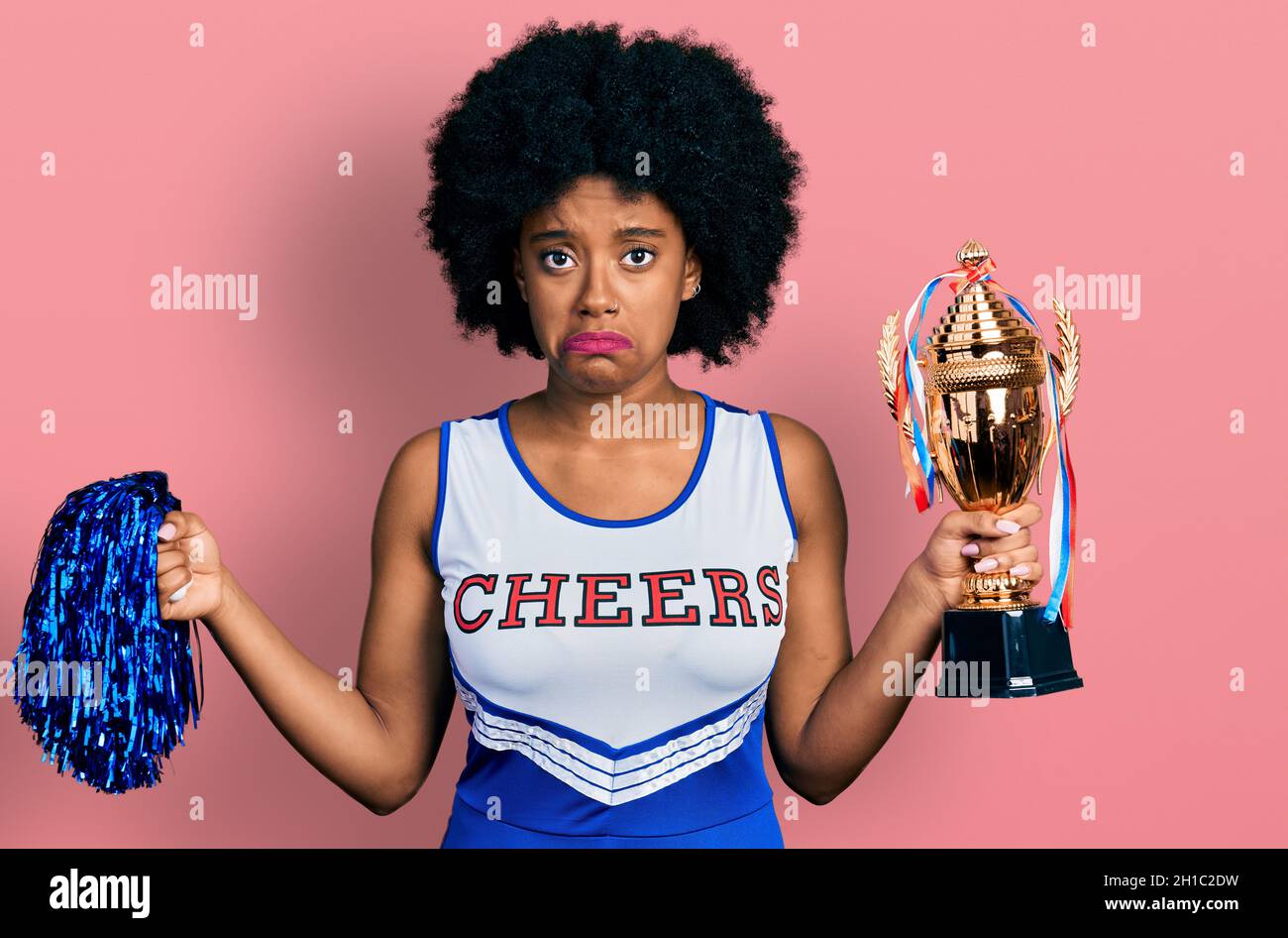 Young african american woman wearing cheerleader uniform holding pompom ...