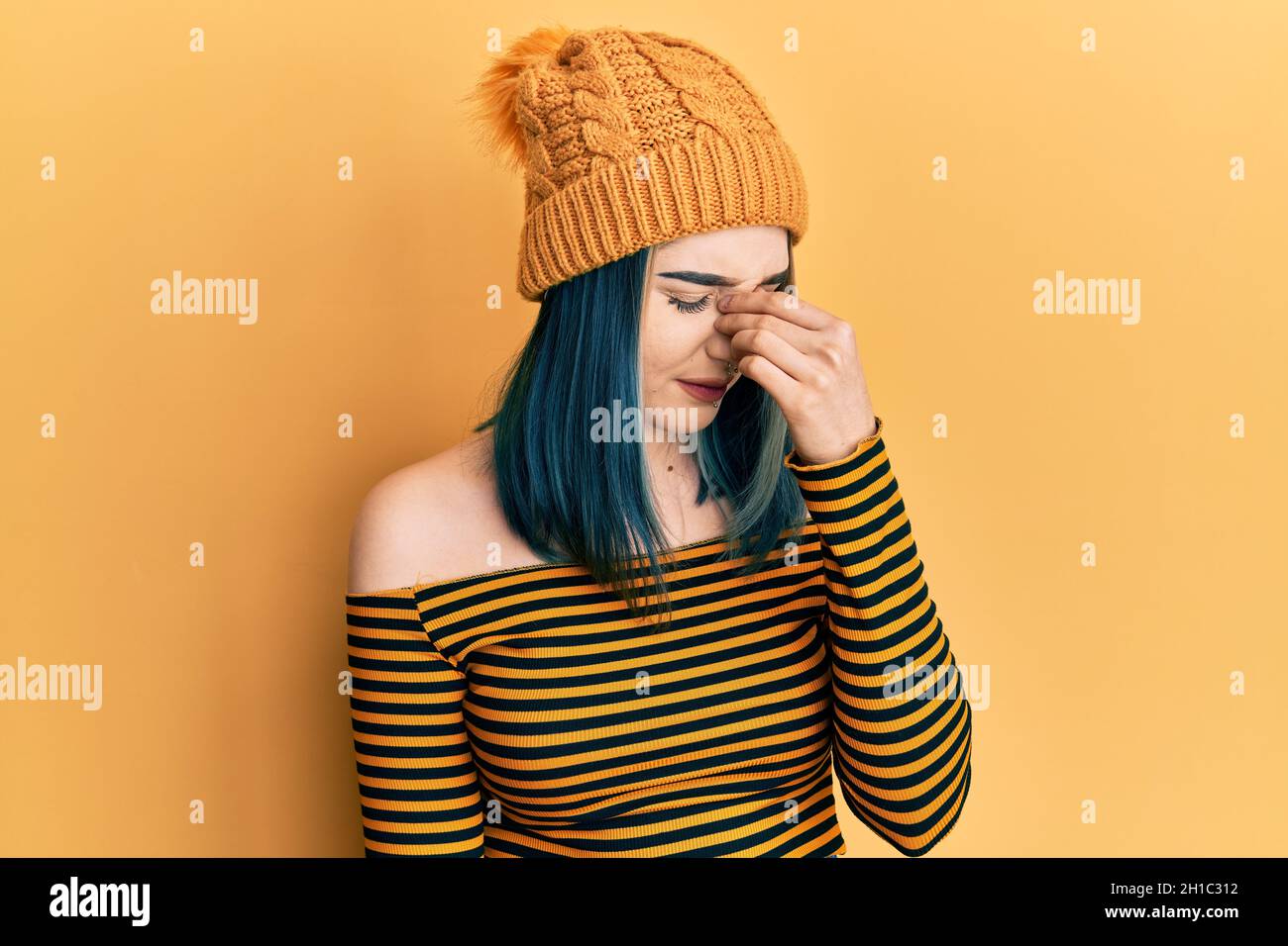 Young modern girl wearing wool hat tired rubbing nose and eyes feeling ...