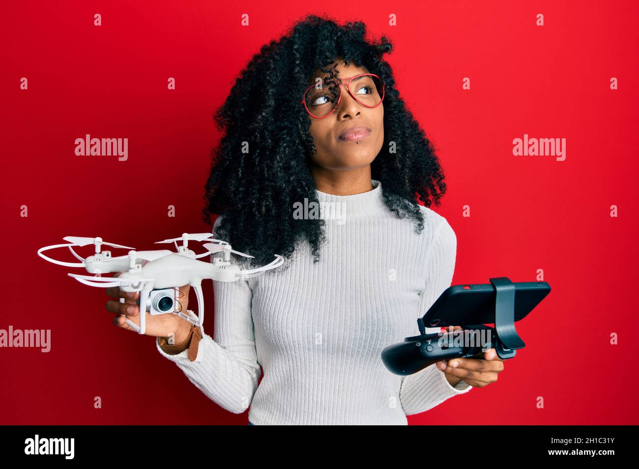 African american woman with afro hair using drone with remote control ...