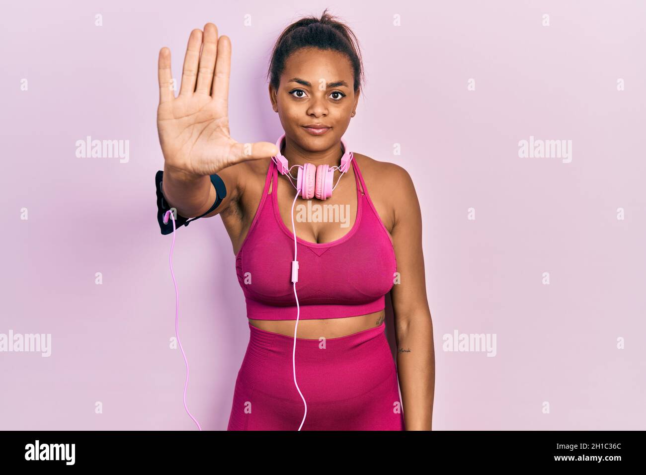 Young african american girl wearing gym clothes and using headphones ...