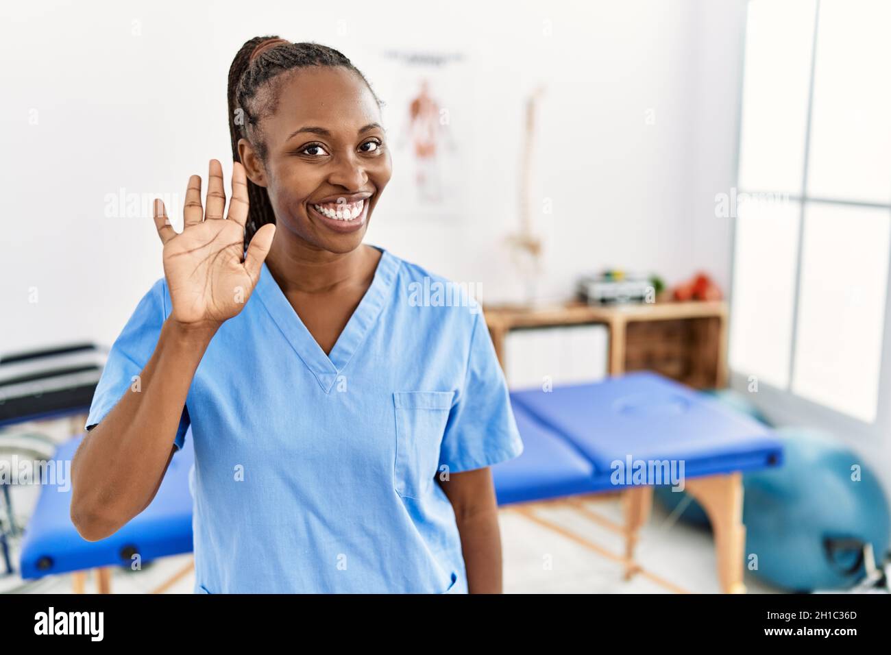 Black woman with braids working at pain recovery clinic waiving saying ...