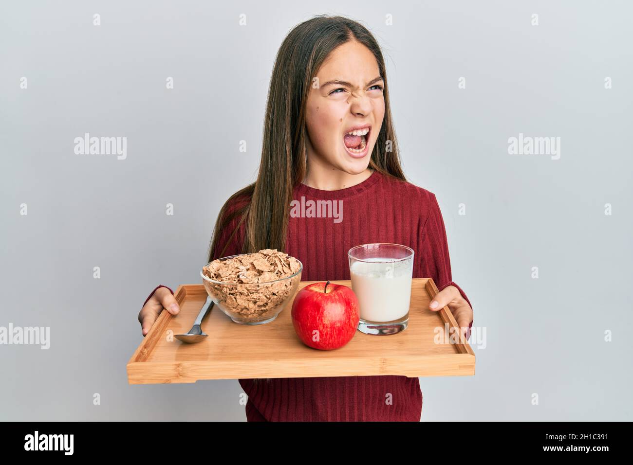Beautiful brunette little girl holding tray with breakfast food angry ...